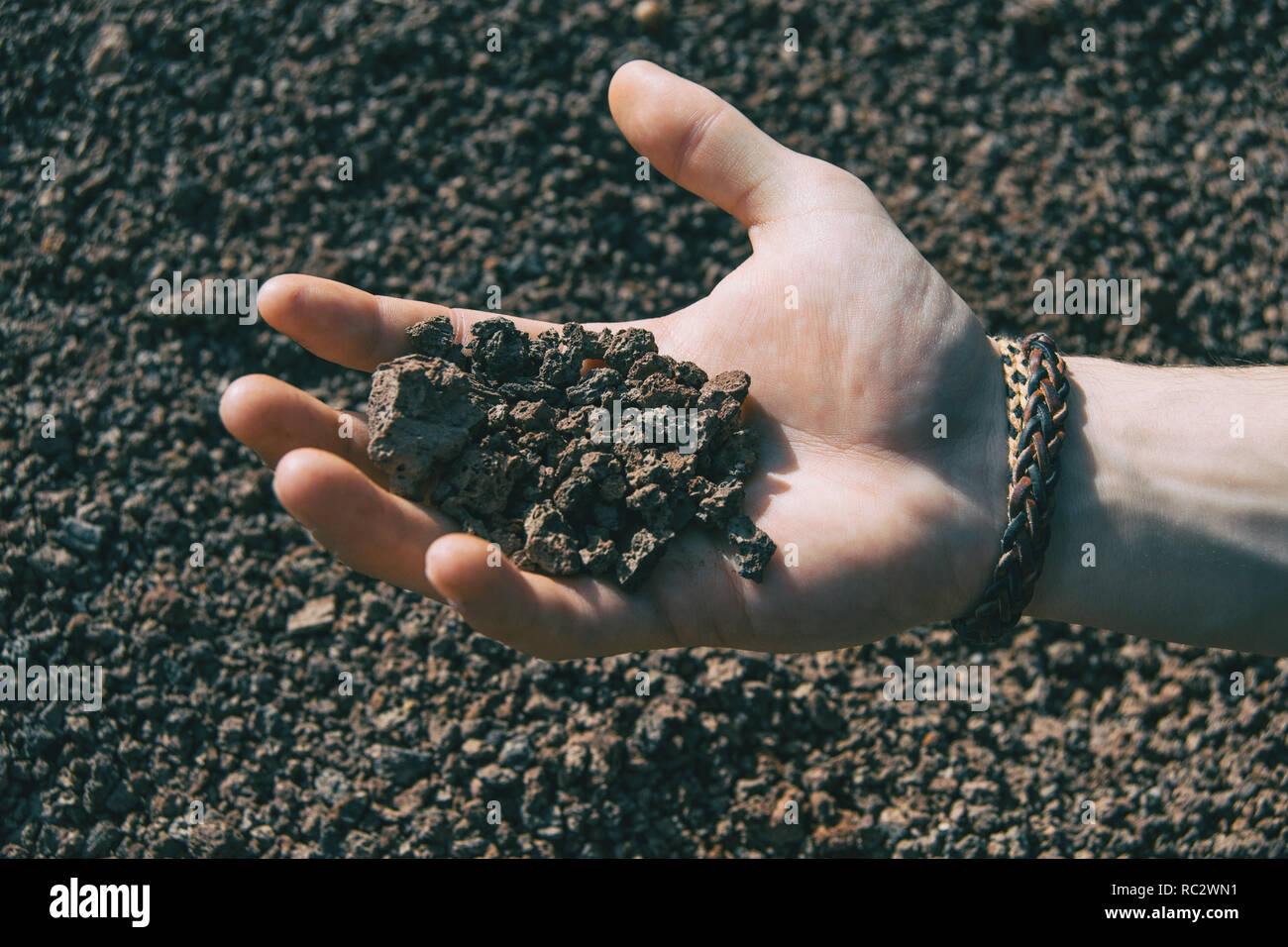 Close-up of a human hand holding some volcanic rocks Stock Photo - Alamy