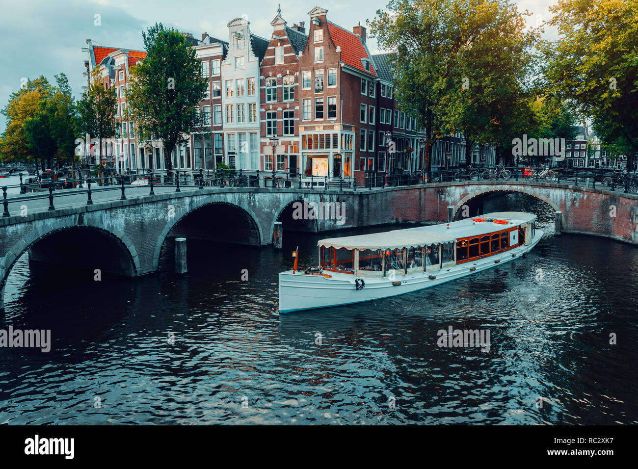 Beautiful view of Amsterdam canals with white cruise boat bridge and ...