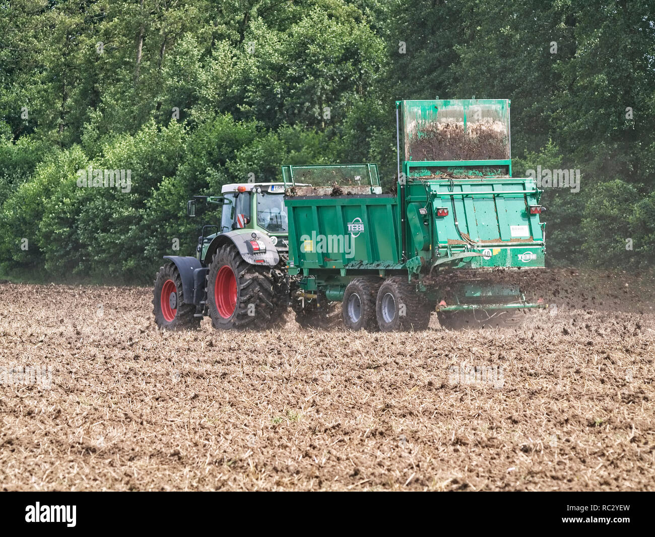 Farmer on his tractor coupled with a manure spreading trailer ...