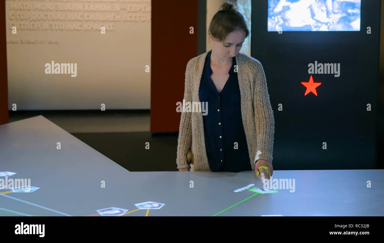 Woman using interactive touchscreen display at modern history museum ...