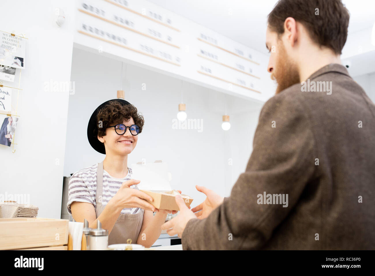 Giving paper box with sweets to customer in bakers shop Stock Photo - Alamy