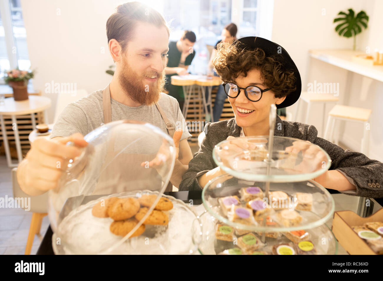 Waiter presenting sweets to customer in cafe Stock Photo - Alamy