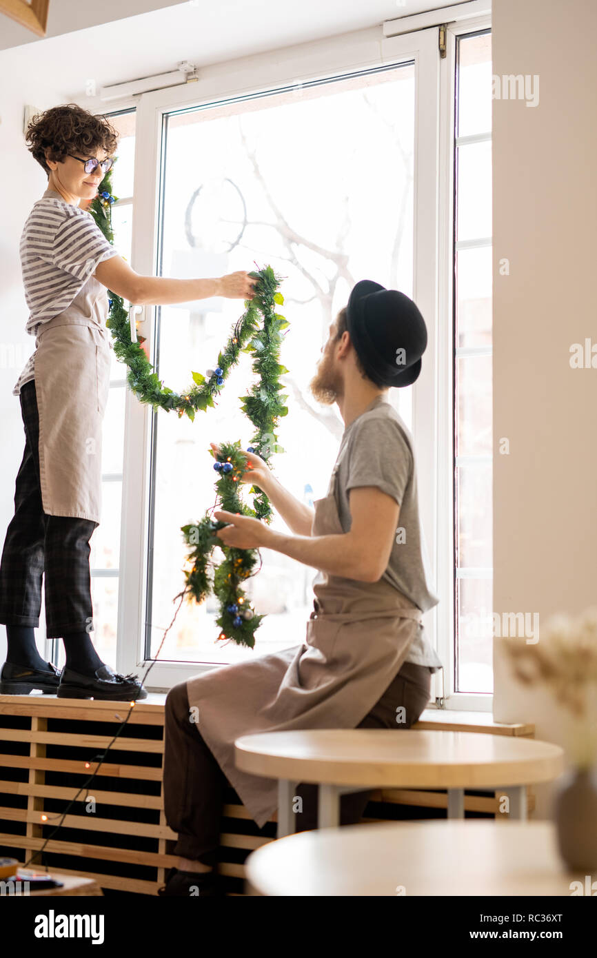Cafe staff decorating window with tinsel Stock Photo - Alamy