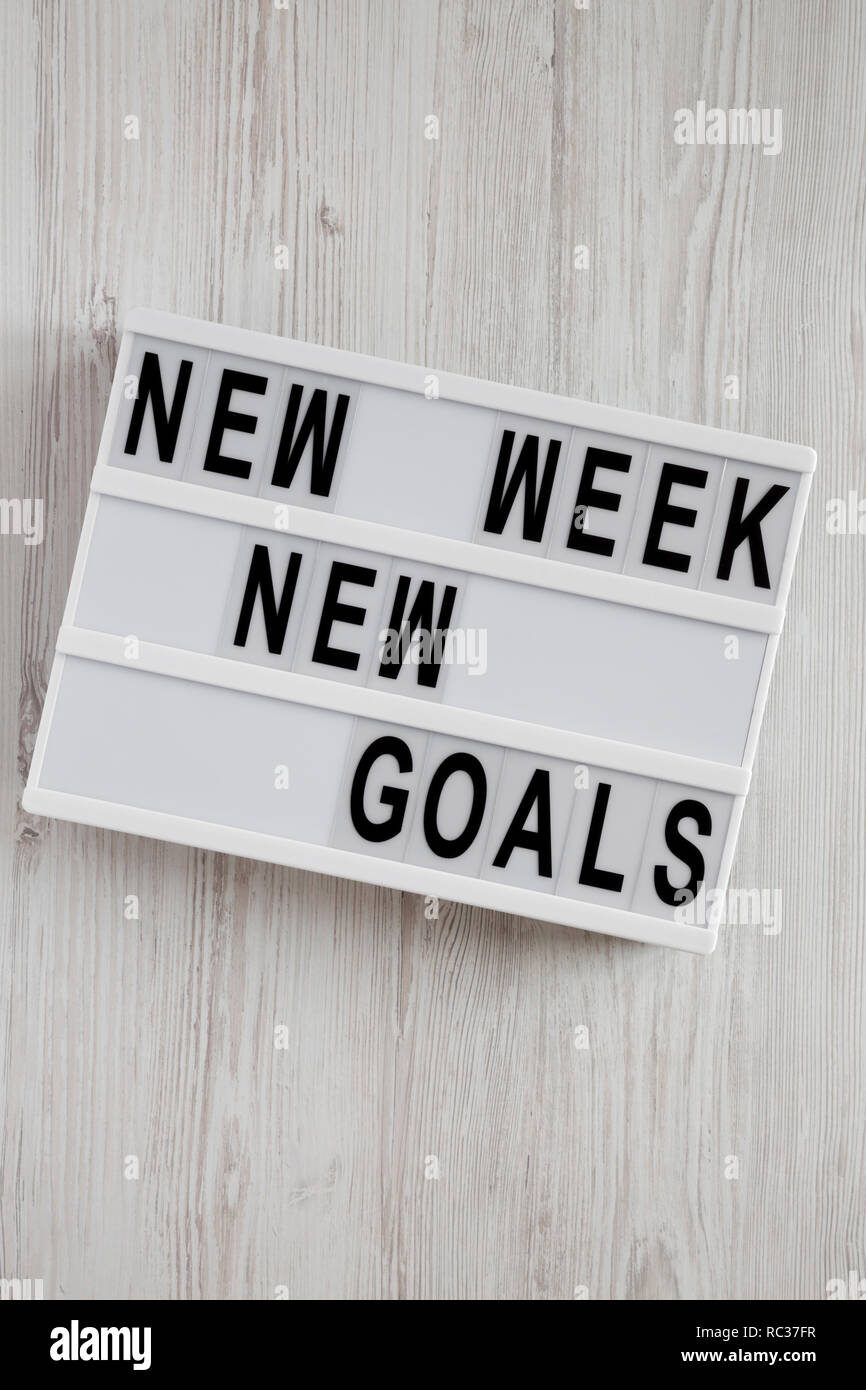Modern board with text 'New week new goals' over white wooden ...