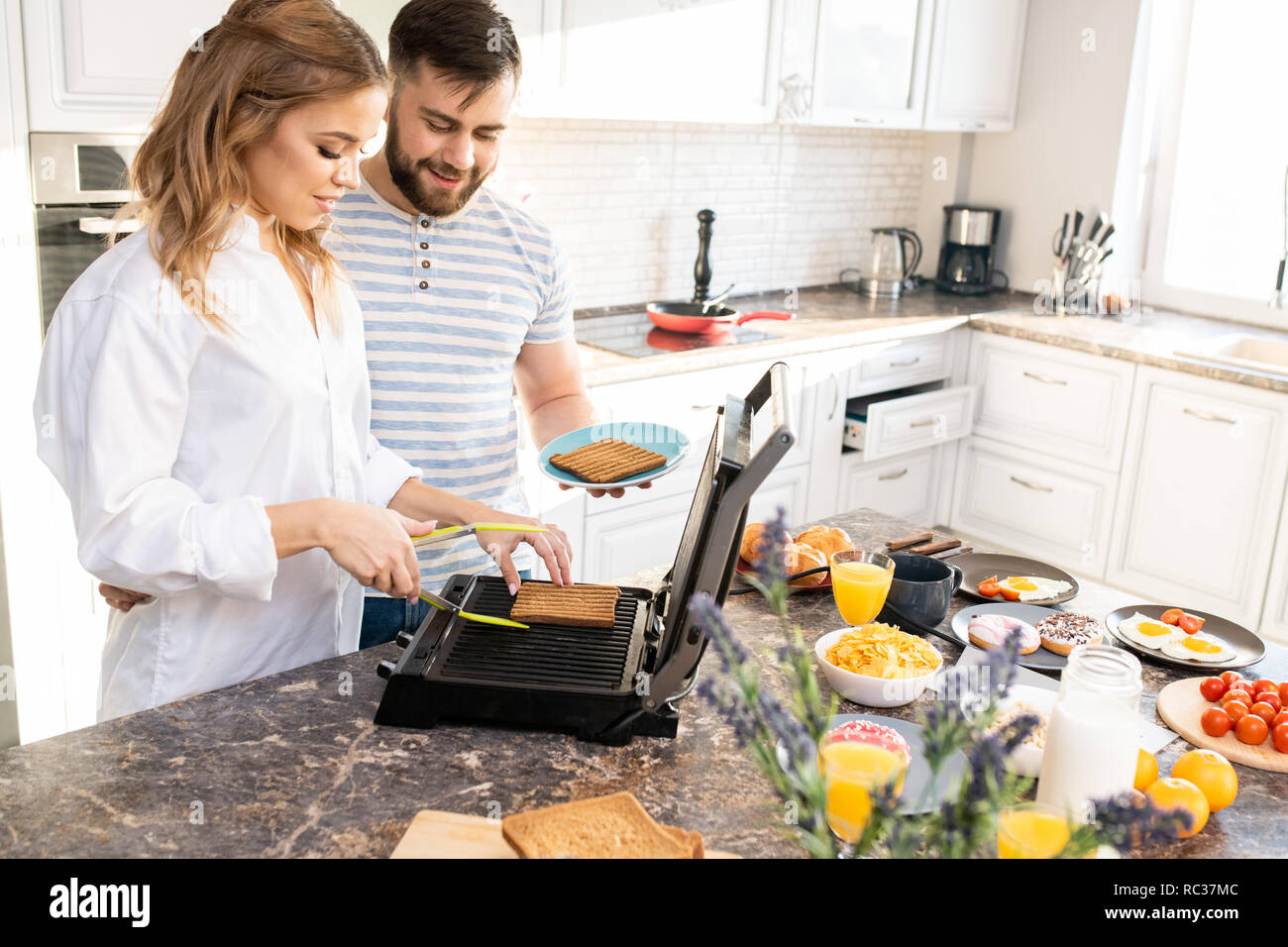 Young Couple Making Toasts in Kitchen Stock Photo - Alamy