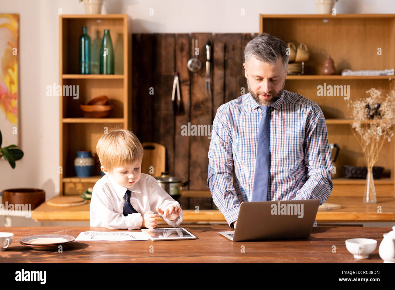 Little son trying to be as father Stock Photo - Alamy