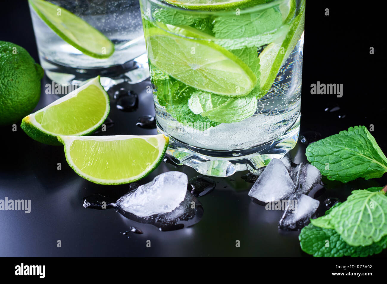 mojito cocktail with lime, fresh mint and ice in glass on dark ...