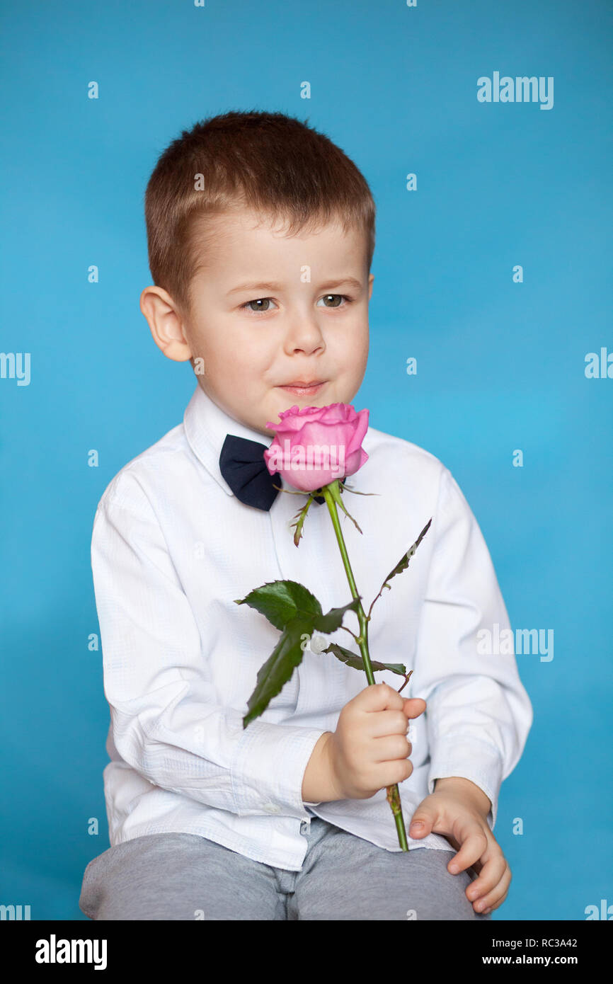A handsome little boy is holding a pink rose Stock Photo - Alamy