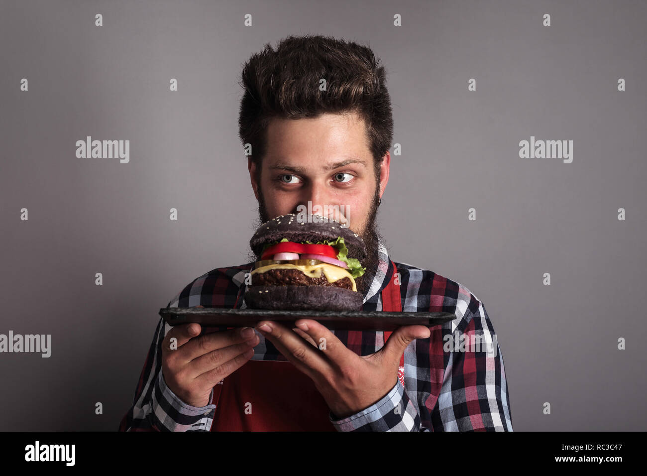 Man smelling fresh self made black burger close up Stock Photo - Alamy