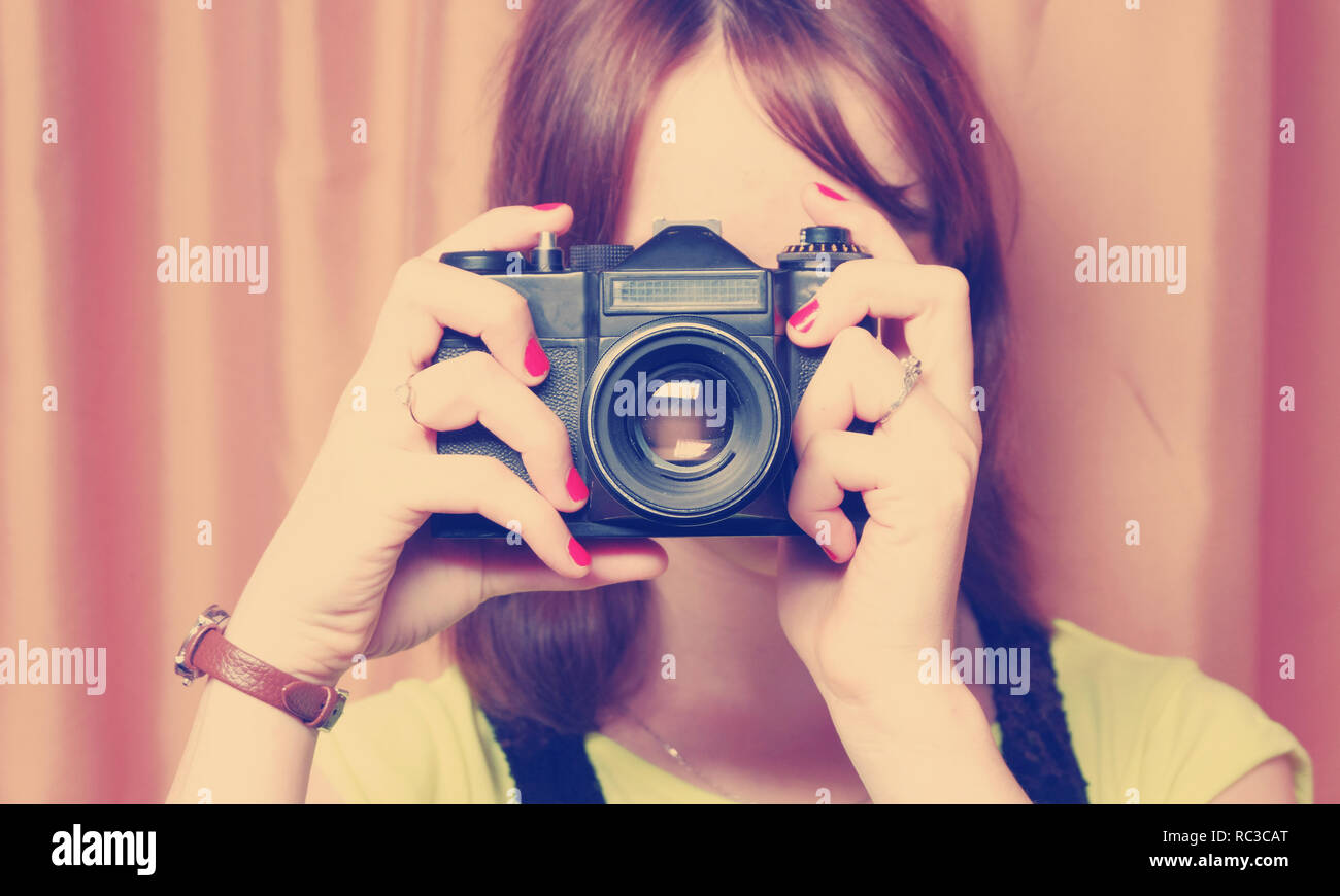 Girl holding vintage photo SLR camera in front of her face, image in ...