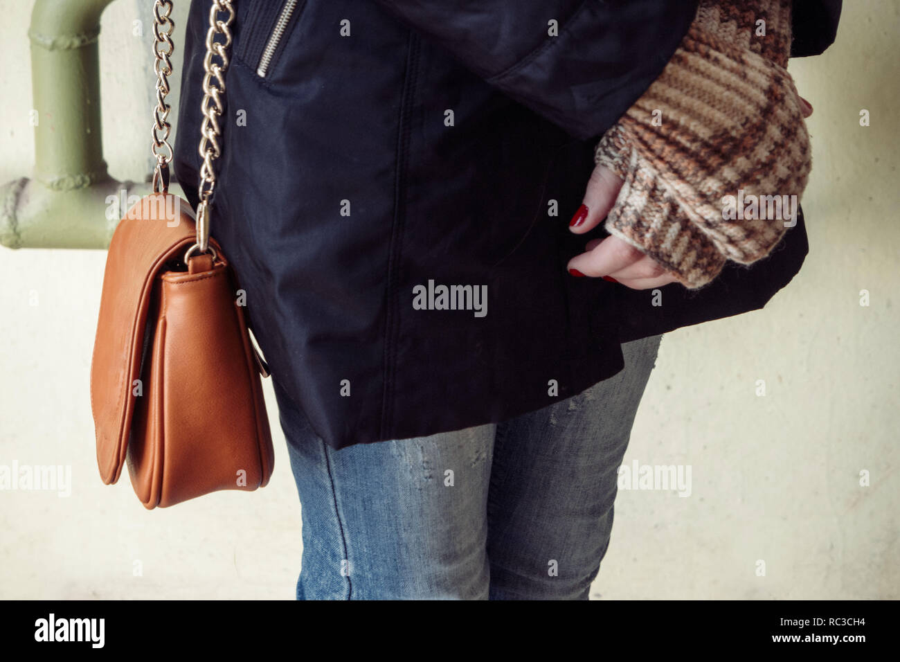 Girl with handbag on her shoulder standing with her hands in knitted ...