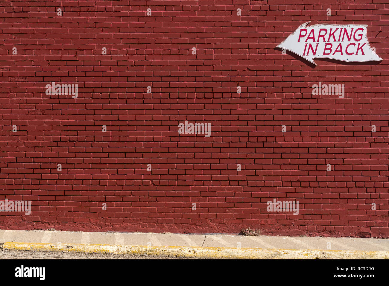 Red painted brick wall with "Parking in Back" sign Stock Photo - Alamy