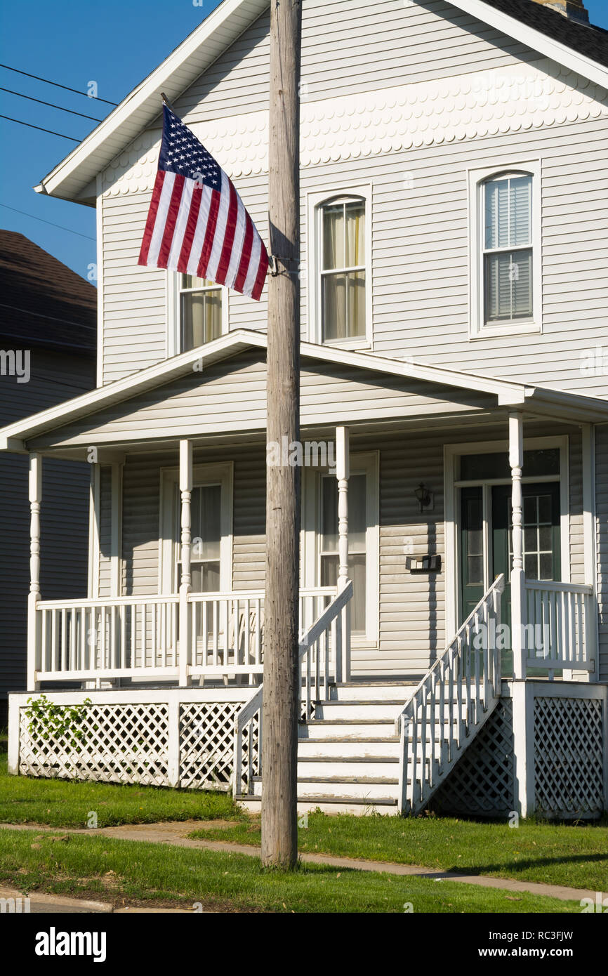 American flag on telephone pole with typical Midwest home in background ...