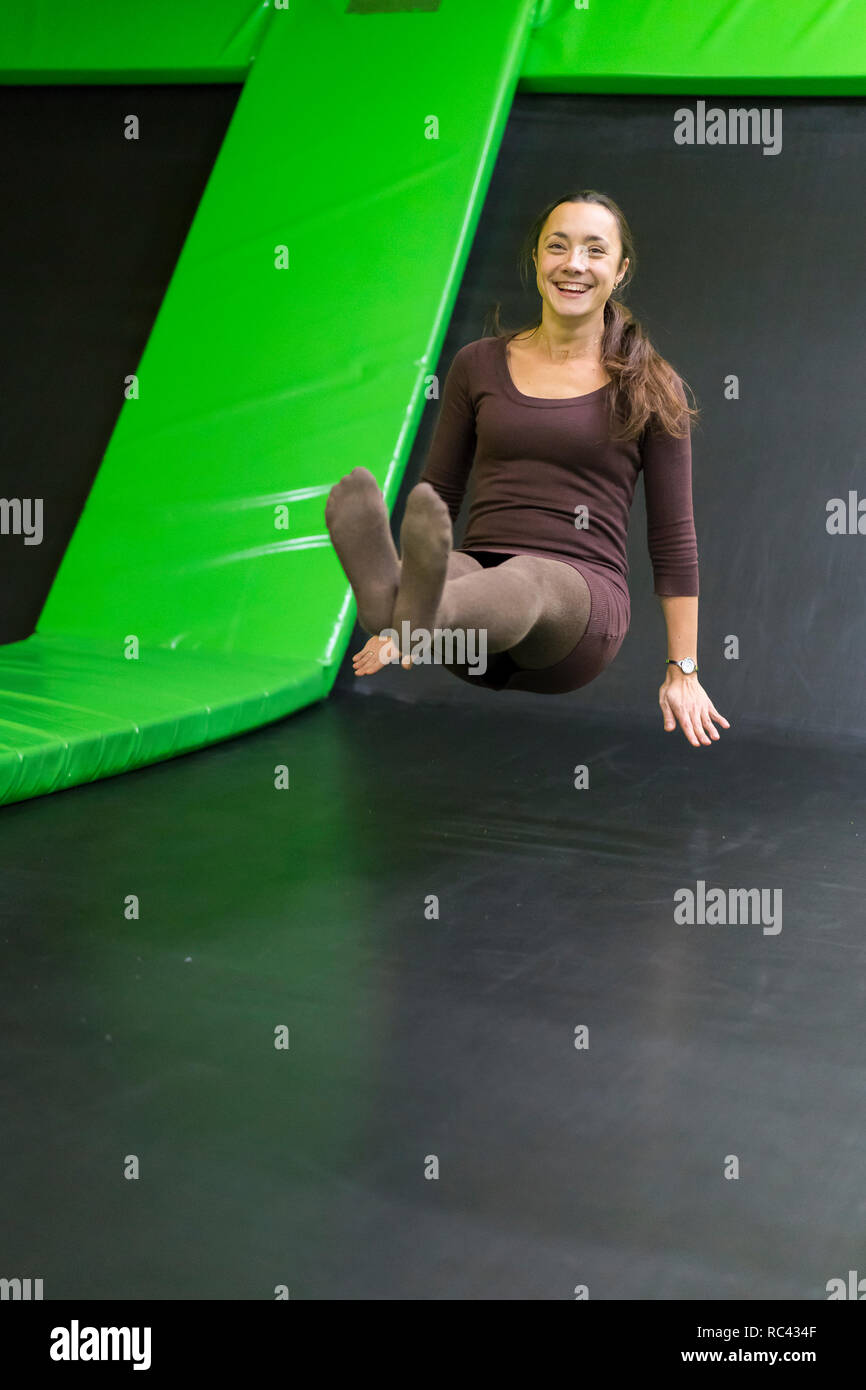 young woman in brown fit dress on trampoline in trampoline center ...