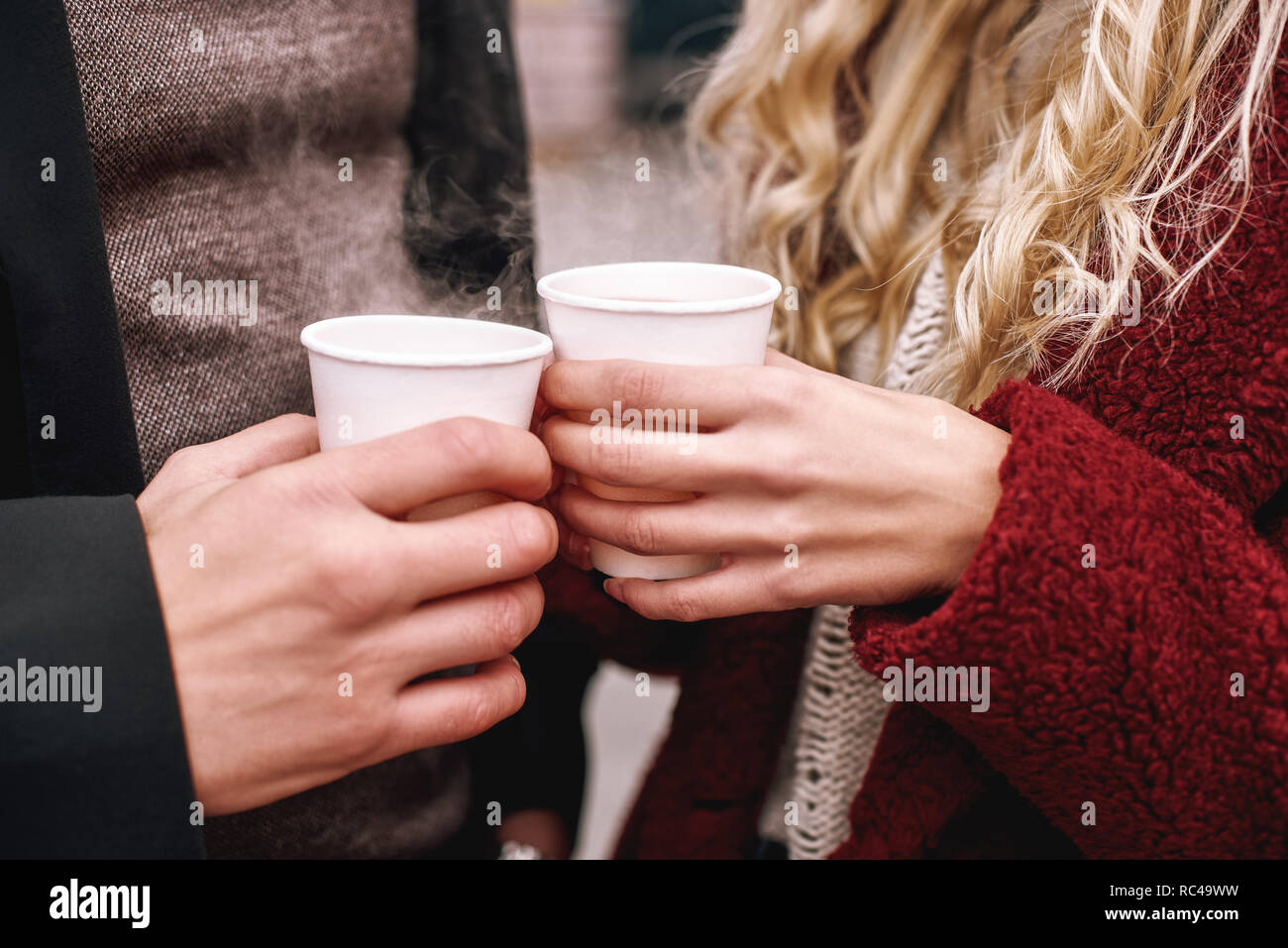 Two cups together. Young couple are drinking hot beverage while ...