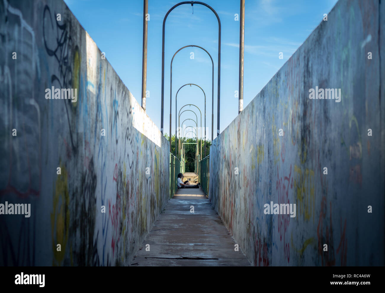Narrow aisle with numerous graffiti. A person sitting in the hall ...