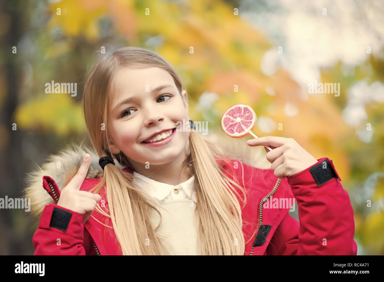 Child point finger at candy on stick outdoor. Girl smile with lollipop ...