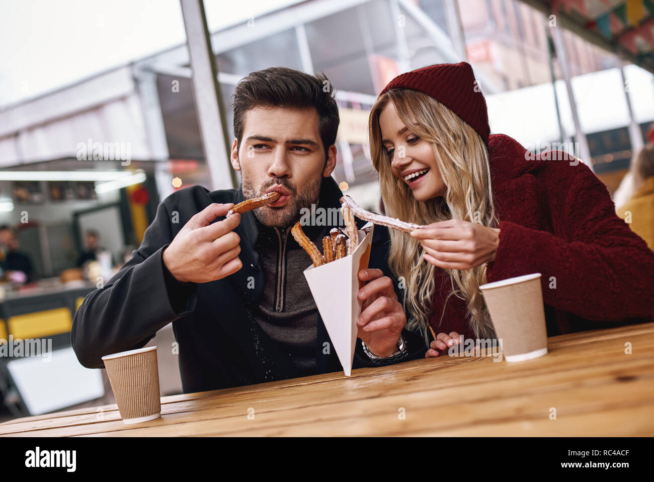 Couple are eating outdoors . Young couple are eating churros at the ...