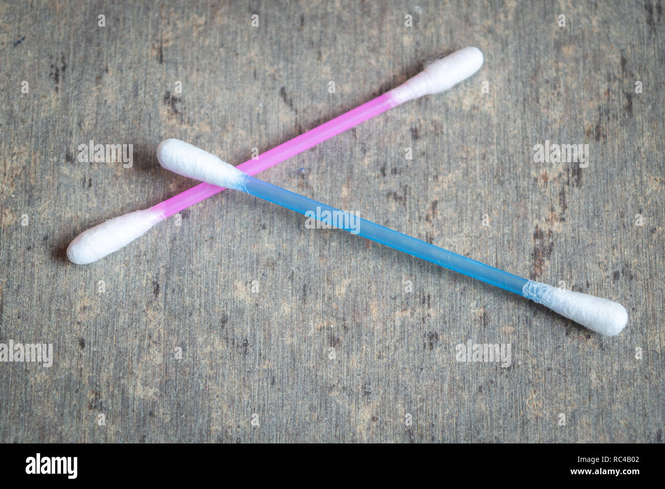 Multi colour cotton swab used for cleaning ears kept on a textured grey ...