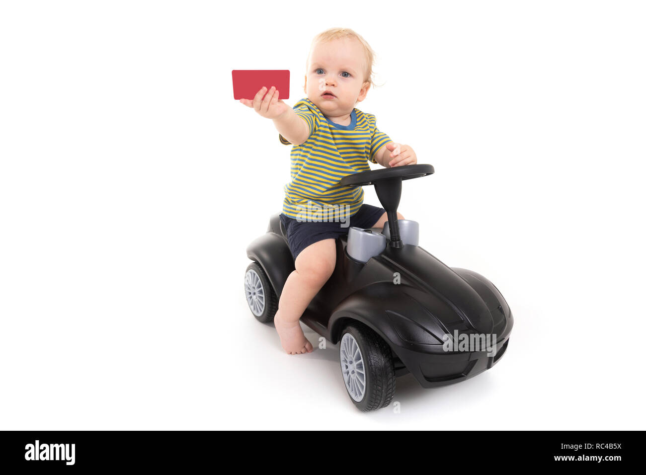 Child with red card in hand sitting on car isolated on white background ...