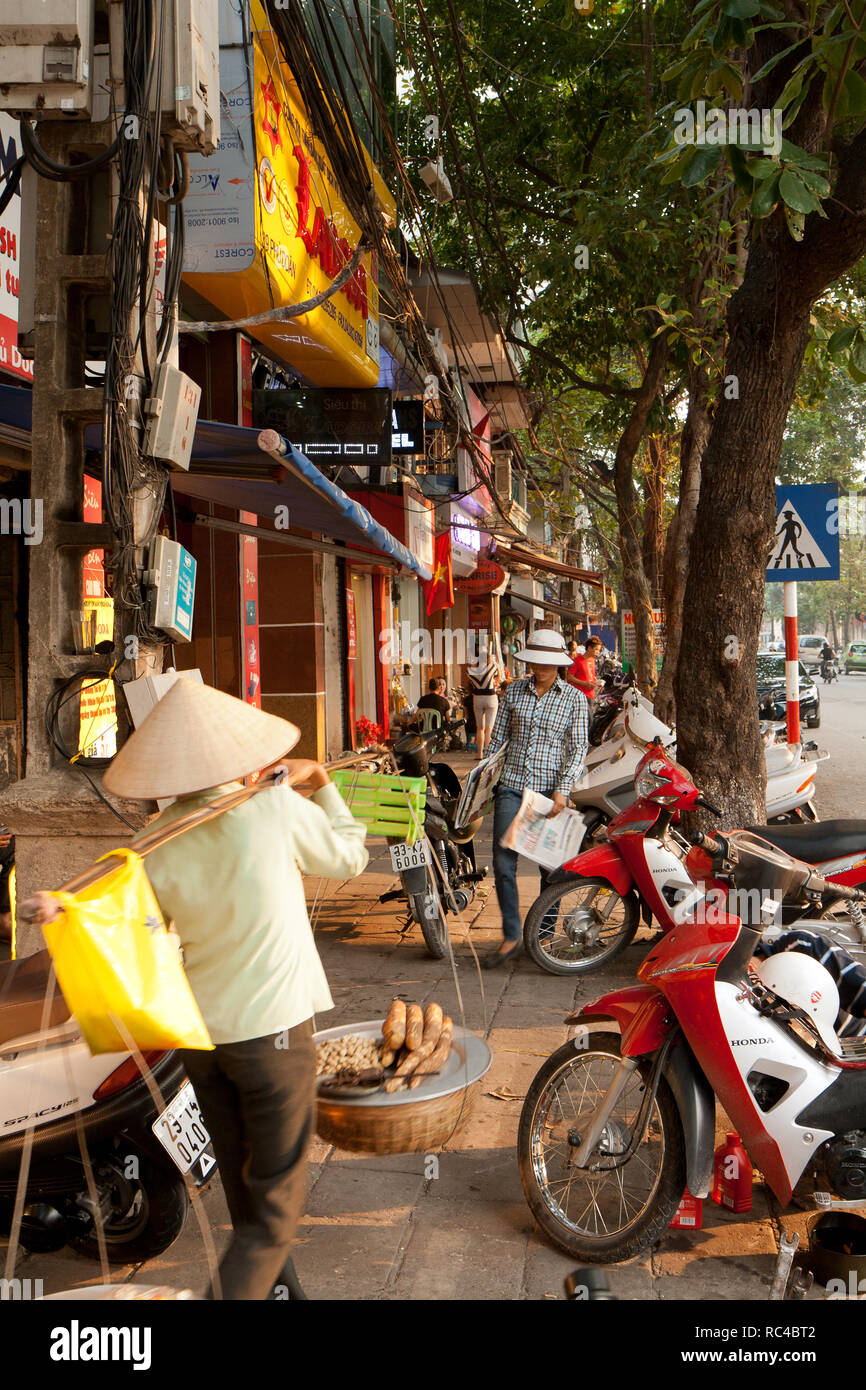 Daily life in Hanoi. Street vendor with baskets and other people ...