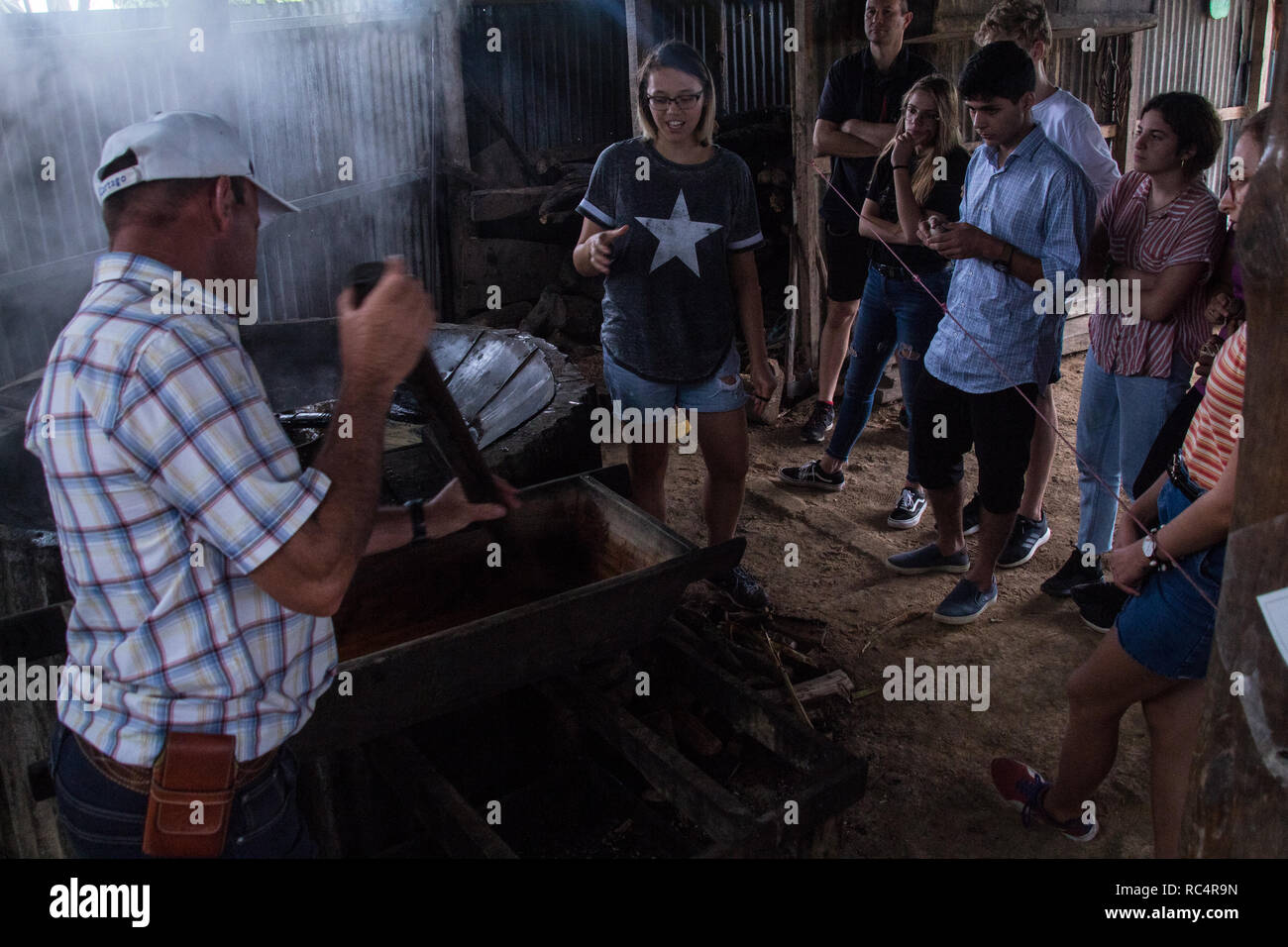 A photo of costa rican farmers showing tourists how to make sugar cane ...