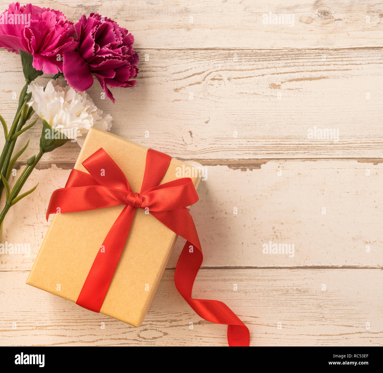 Kraft gift box with red ribbon bow and carnation, concept of giving ...