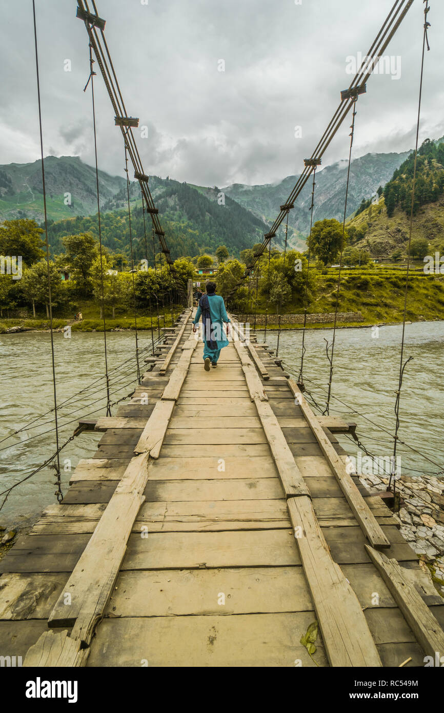 A woman crossing river Indus on dangerously looking bridge in Pakistan ...