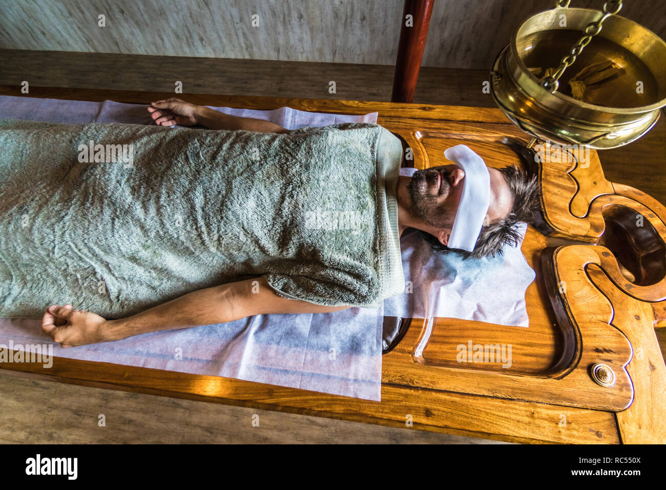 Dripping of oil on forehead. Young man relaxing in Indian spa Stock ...