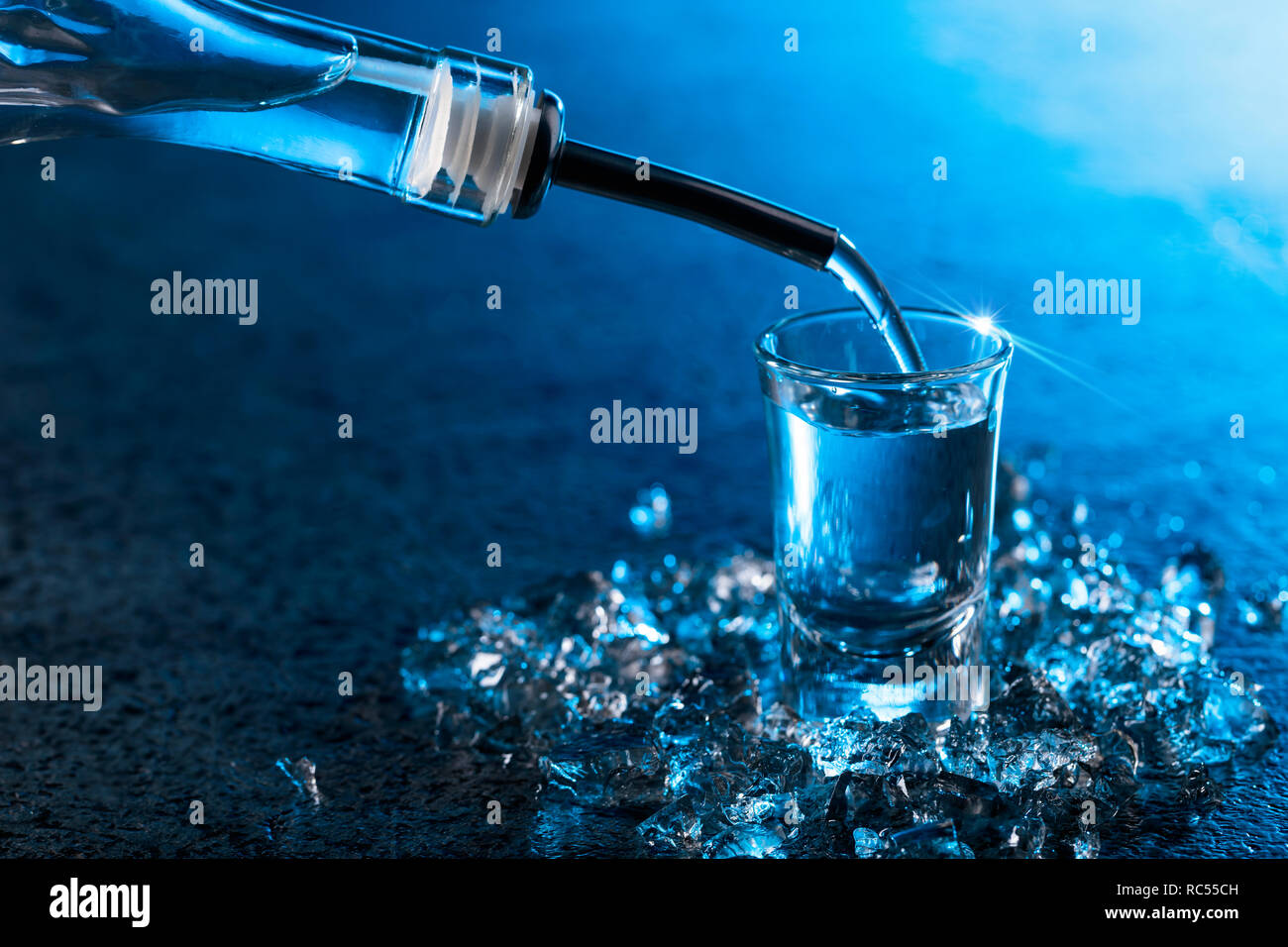 Vodka poured into a glass lit with blue backlight. Copy space.Chilled ...