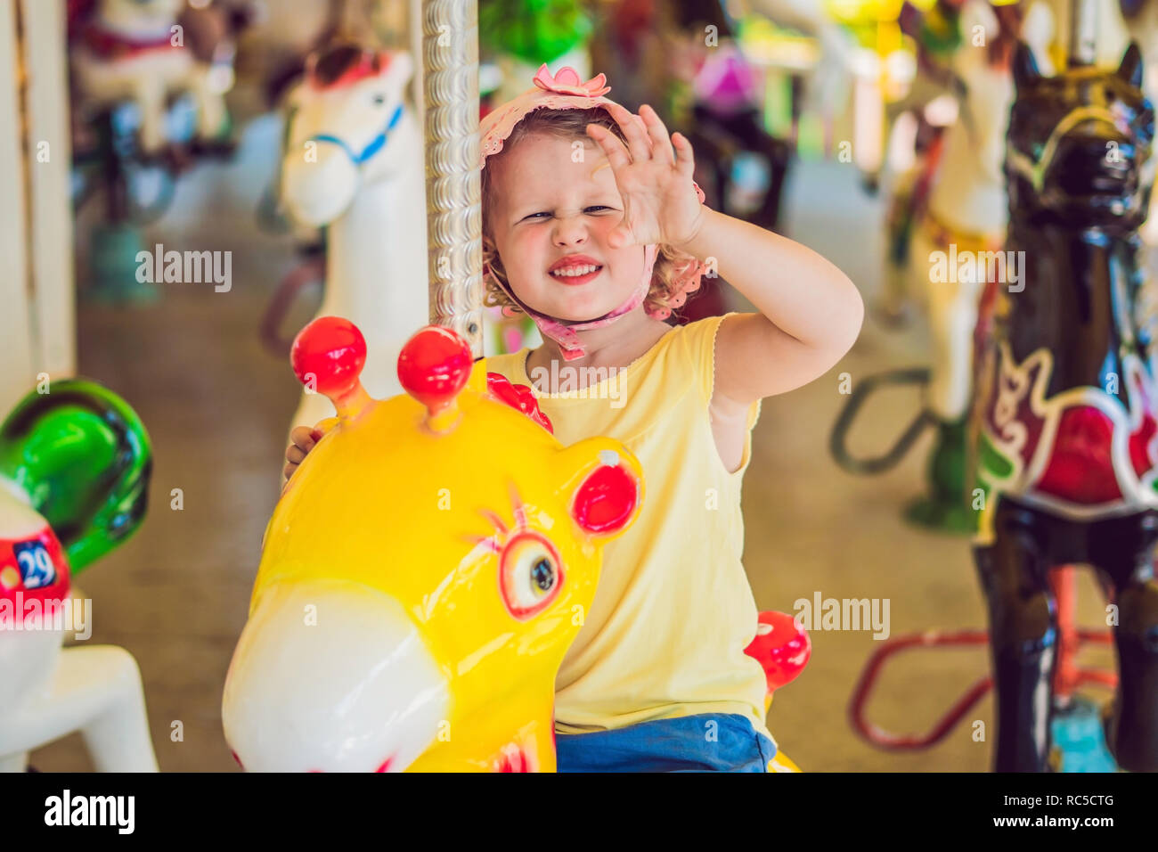 Cute little girl enjoying in funfair and riding on colorful carousel ...