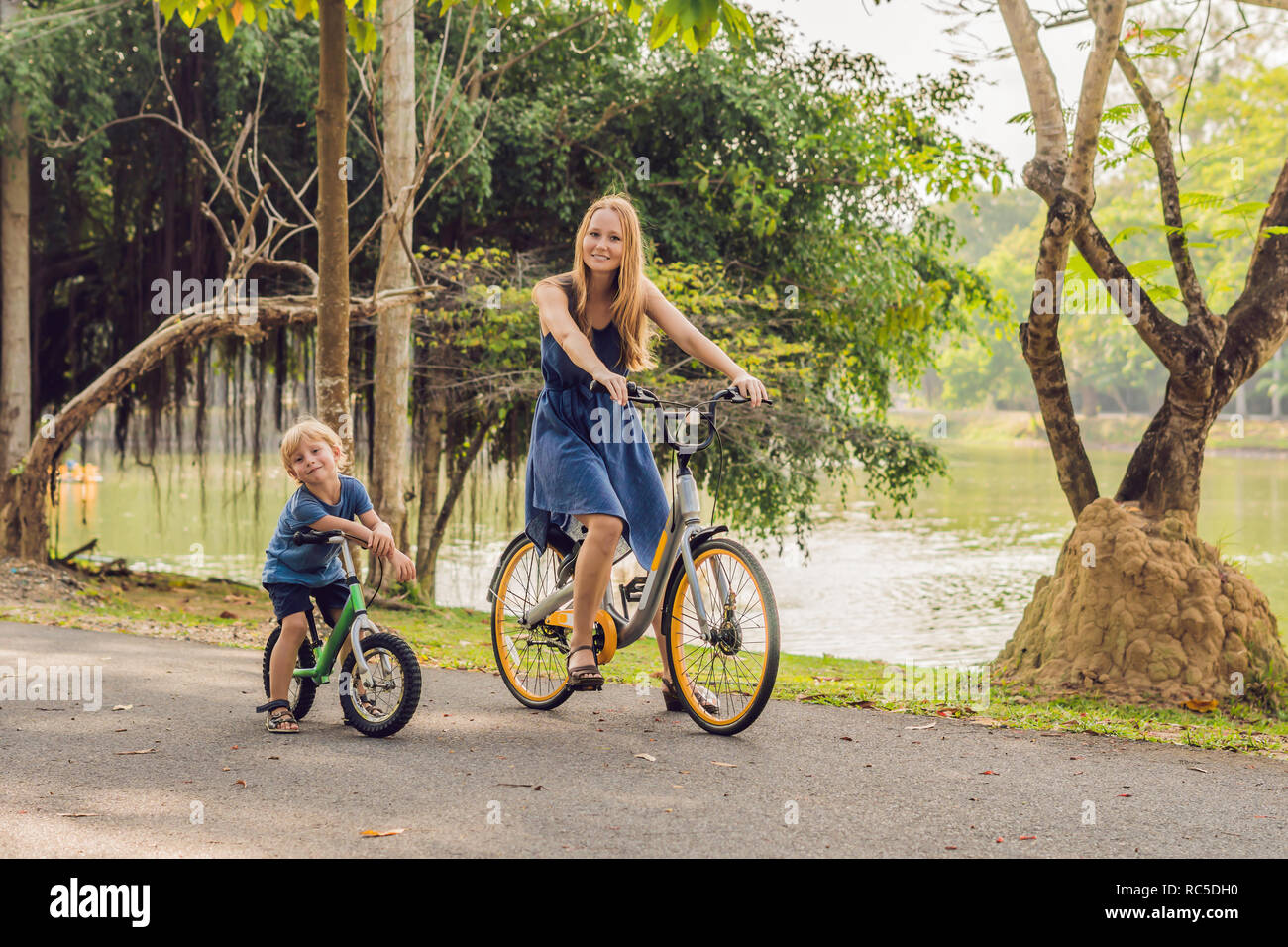 Happy family is riding bikes outdoors and smiling. Mom on a bike and ...