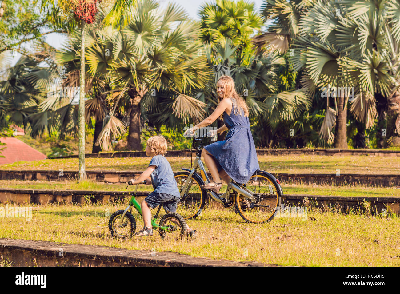 Happy family is riding bikes outdoors and smiling. Mom on a bike and ...