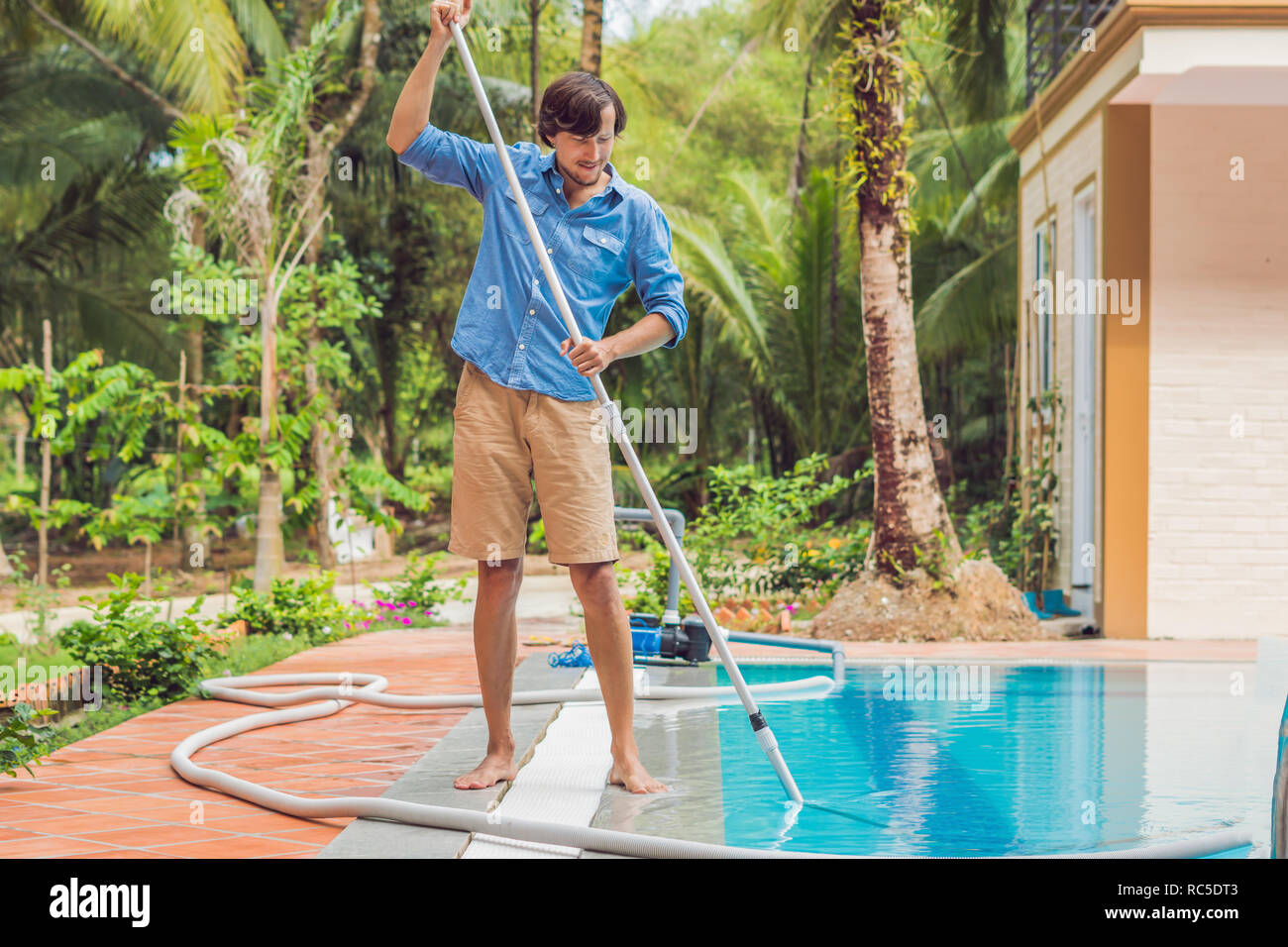 Cleaner of the swimming pool . Man in a blue shirt with cleaning ...