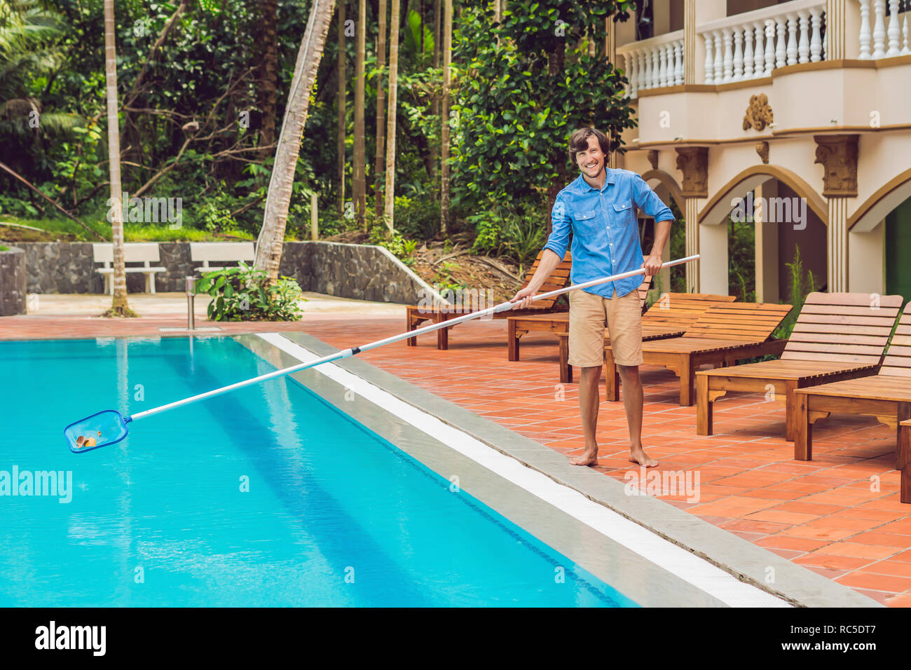 Cleaner of the swimming pool . Man in a blue shirt with cleaning ...
