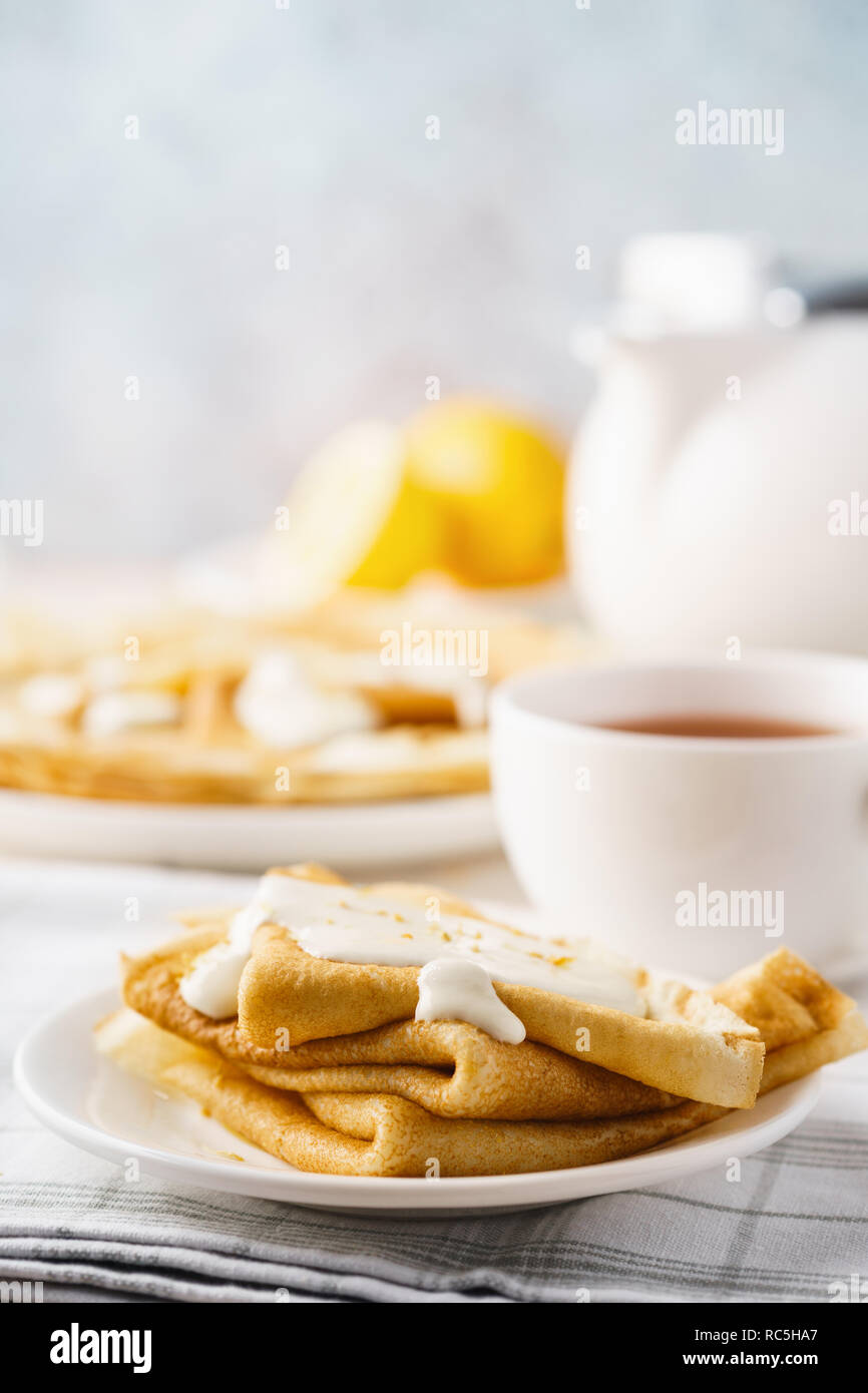 Homemade lemon crepes with custard sauce and tea. Traditional pastry ...