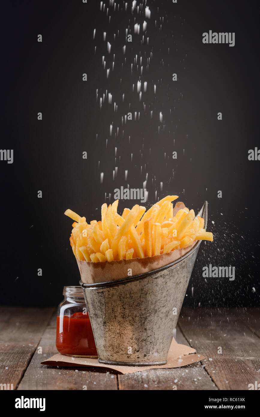 Adding salt to French fries Stock Photo - Alamy