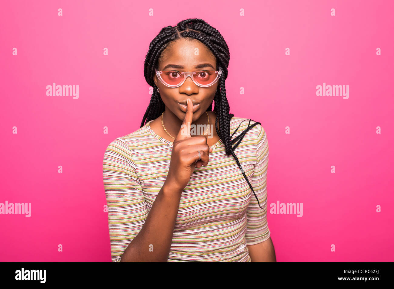 Image of african woman holding index finger on lips and asking to keep ...