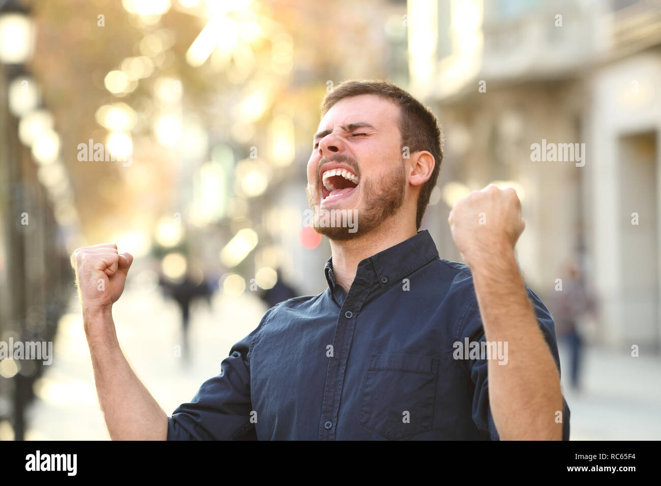 Portrait of an excited guy celebrating success in a city street Stock ...