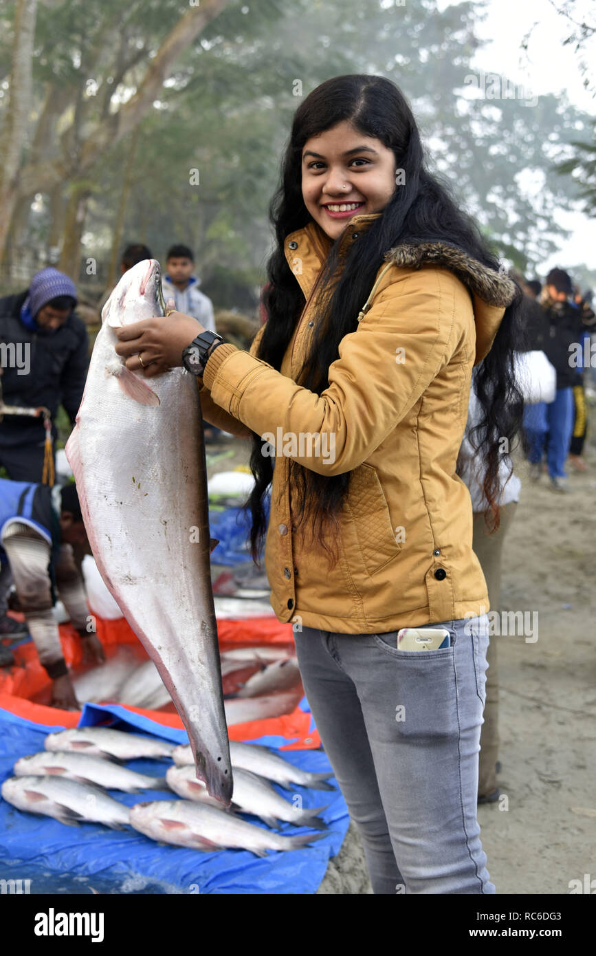 Guwahati, Assam, India. 14th Jan 2019. A girl displays a fish purchased ...