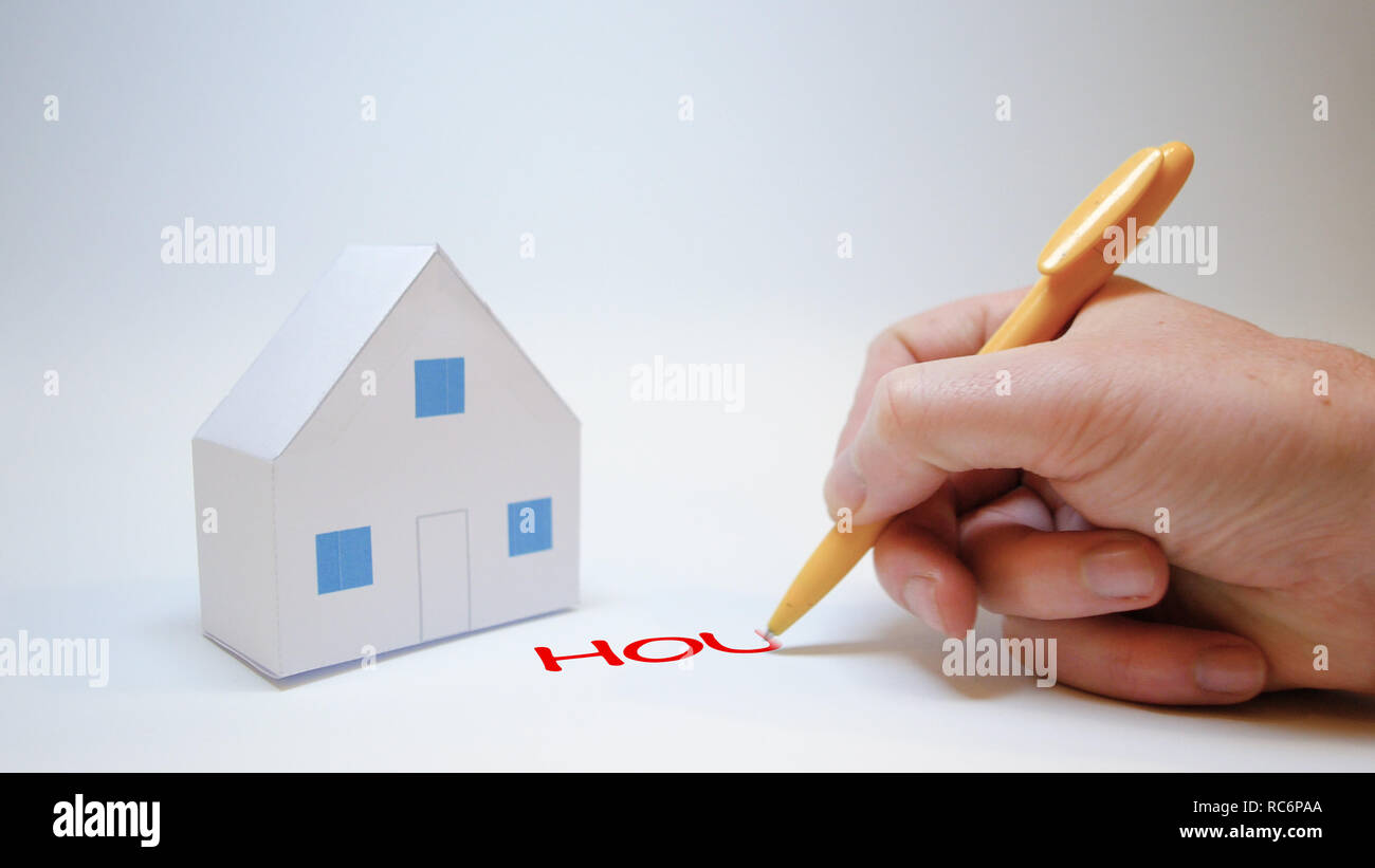 hand writes house writing next to a paper house Stock Photo - Alamy
