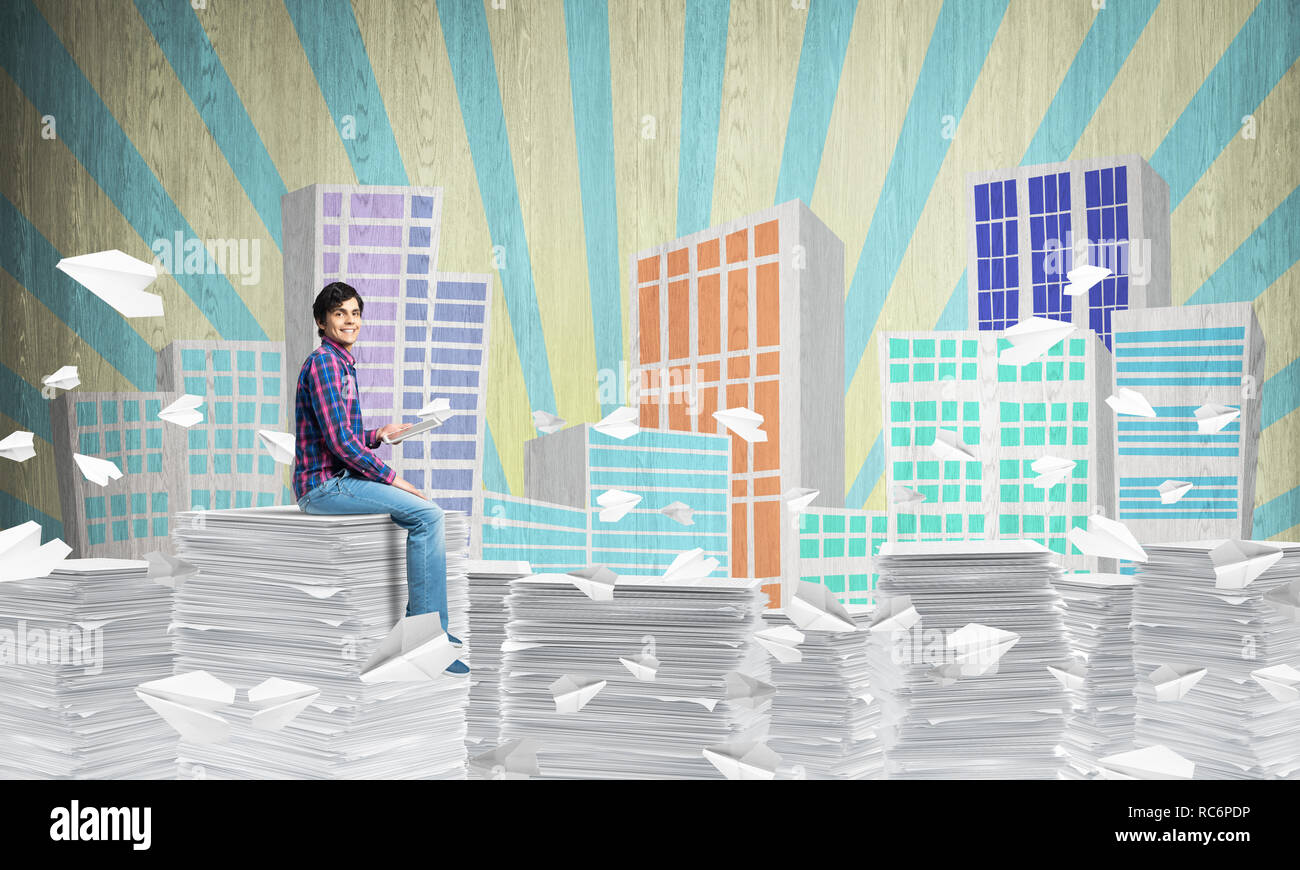 Young man sitting on pile of paper documents Stock Photo - Alamy