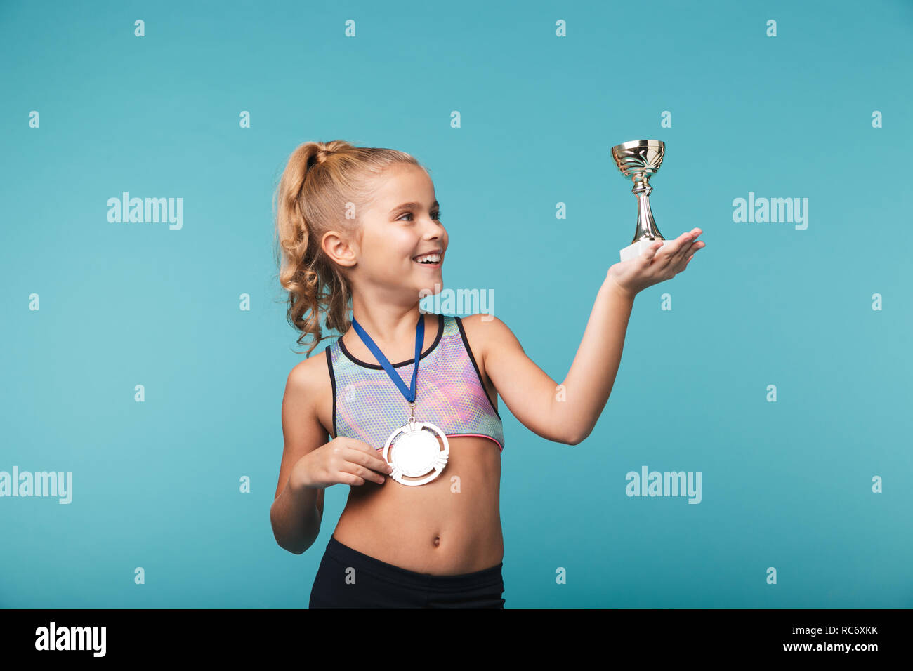 Cheerful little sports girl celebrating the win isolated over blue ...