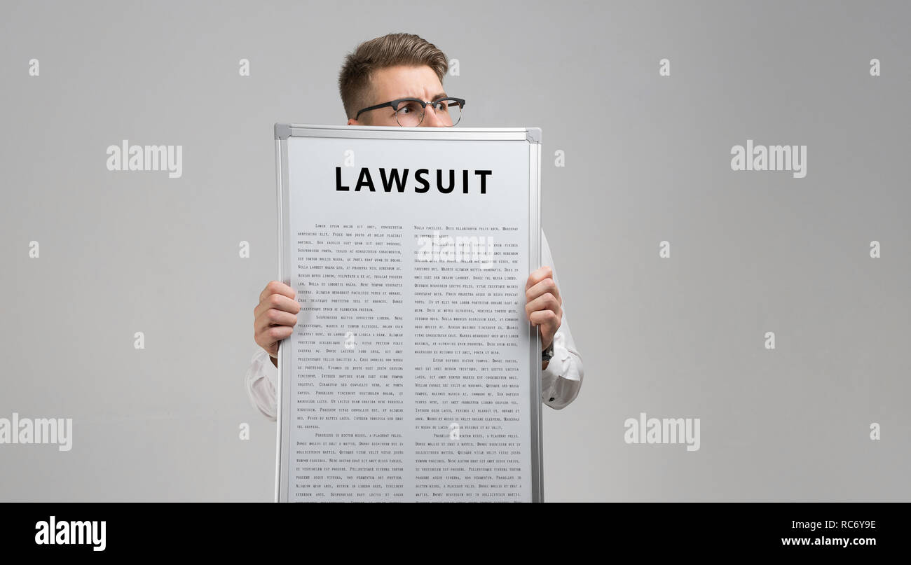 young man keeps in front of him a poster with the inscription lawsuit ...