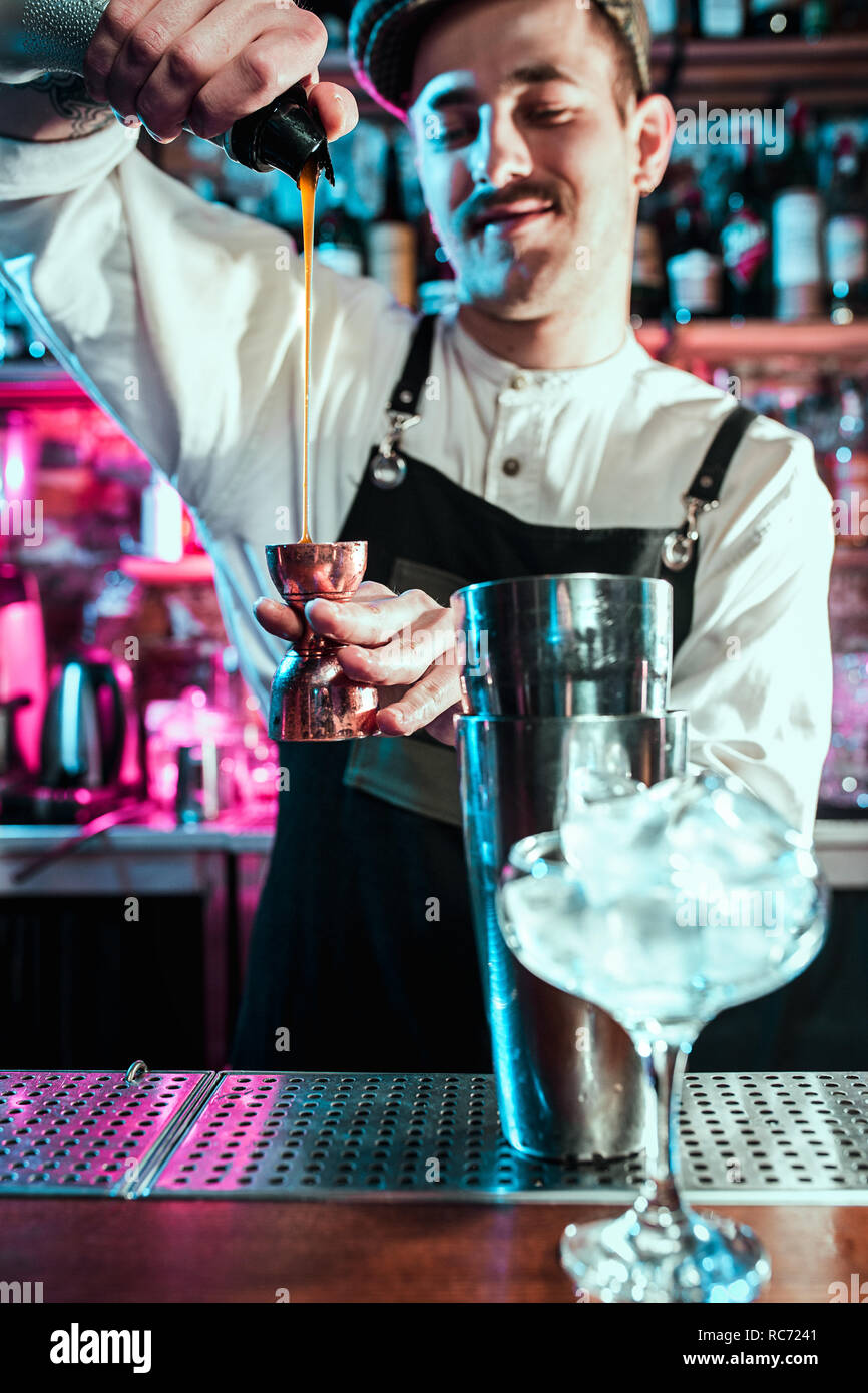 Expert barman is making cocktail at night club or bar. Glass of fiery ...