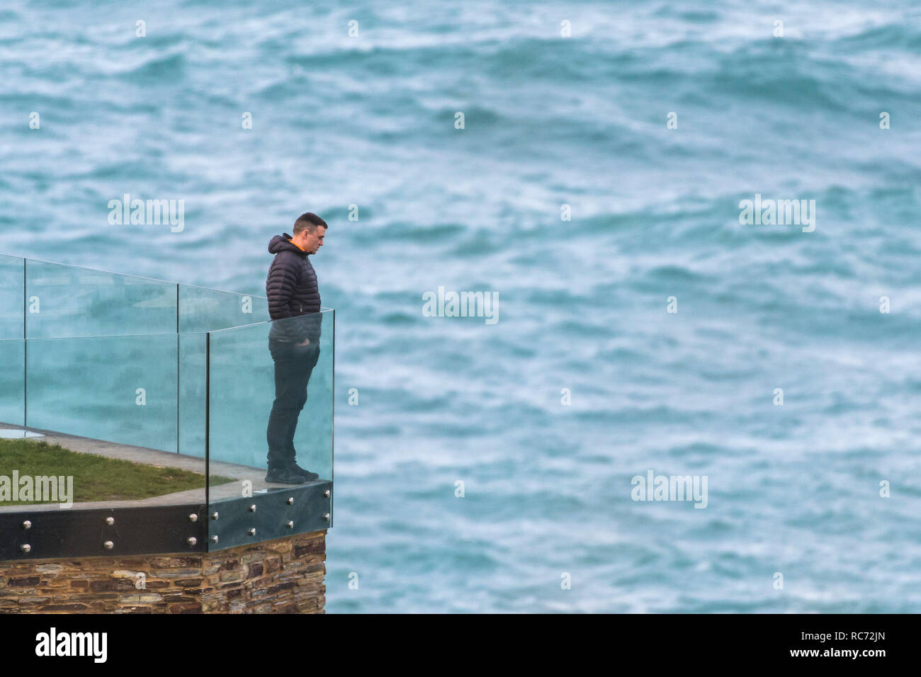 A man standing alone on a balcony looking down at the sea Stock Photo ...