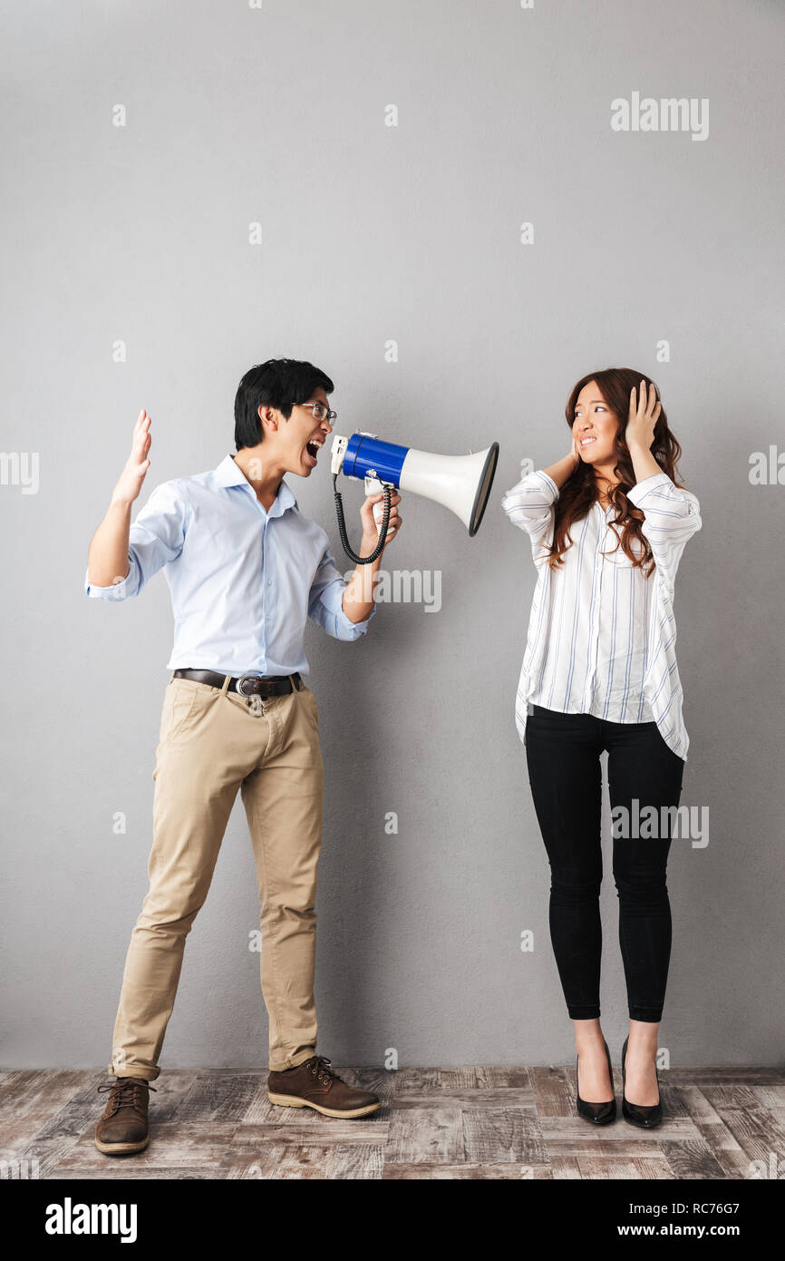 Angry asian business couple standing isolated over gray background, man ...