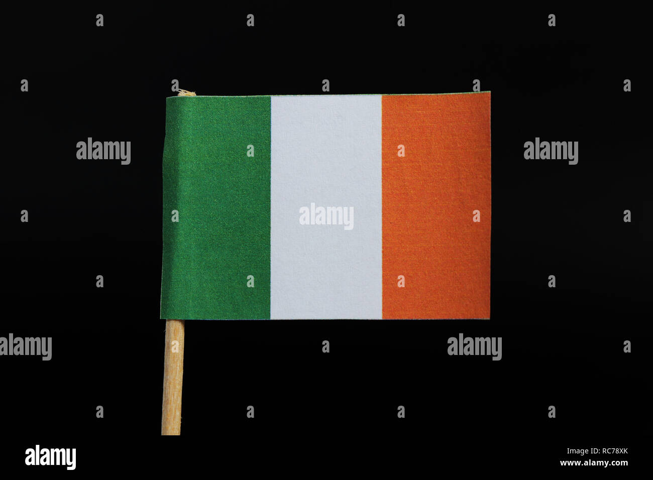 A tricolour flag of Ireland on toothpick on black background. A ...
