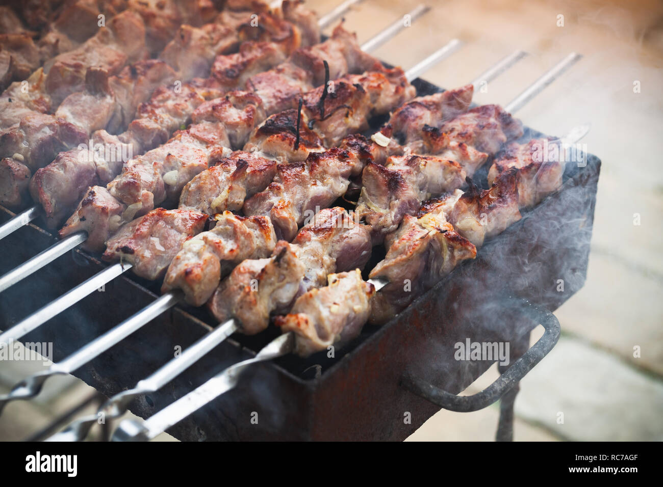 Cooking of pork shashlik on coals, a dish of skewered and grilled cubes ...