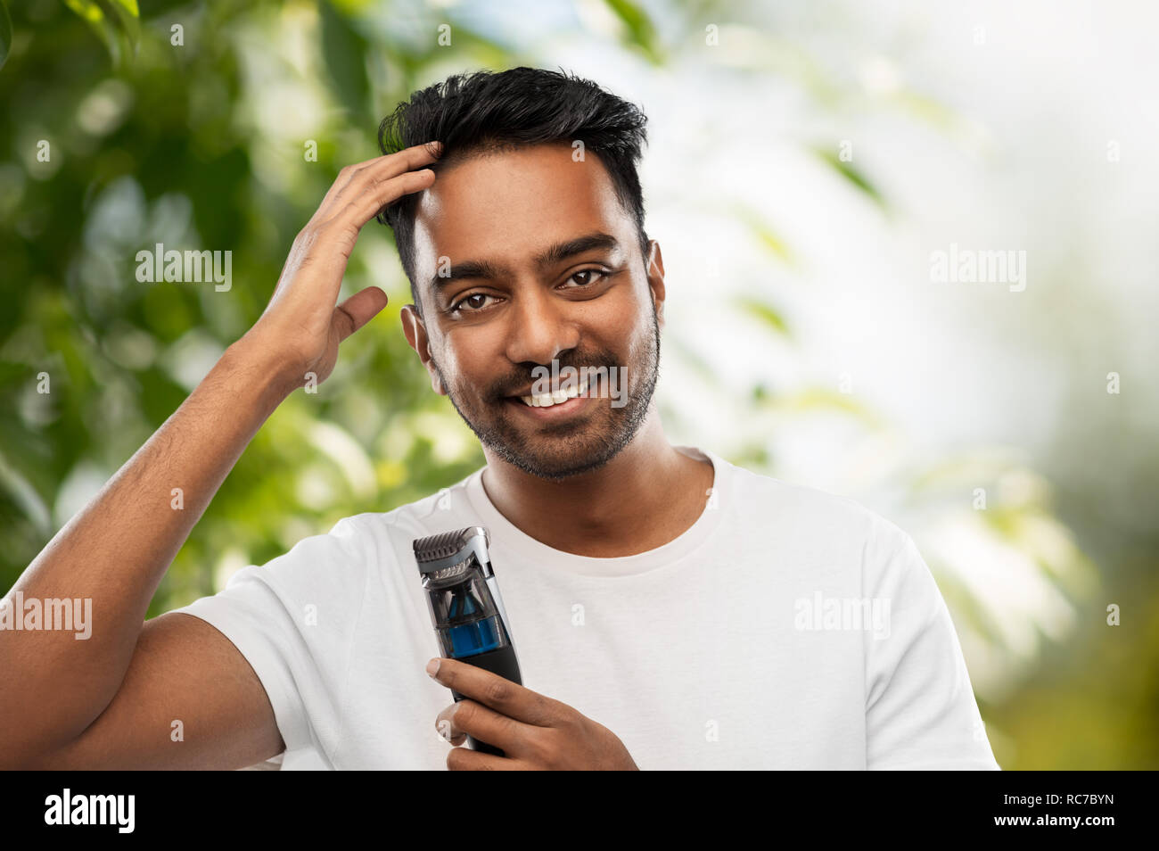 smiling indian man with trimmer touching his hair Stock Photo - Alamy